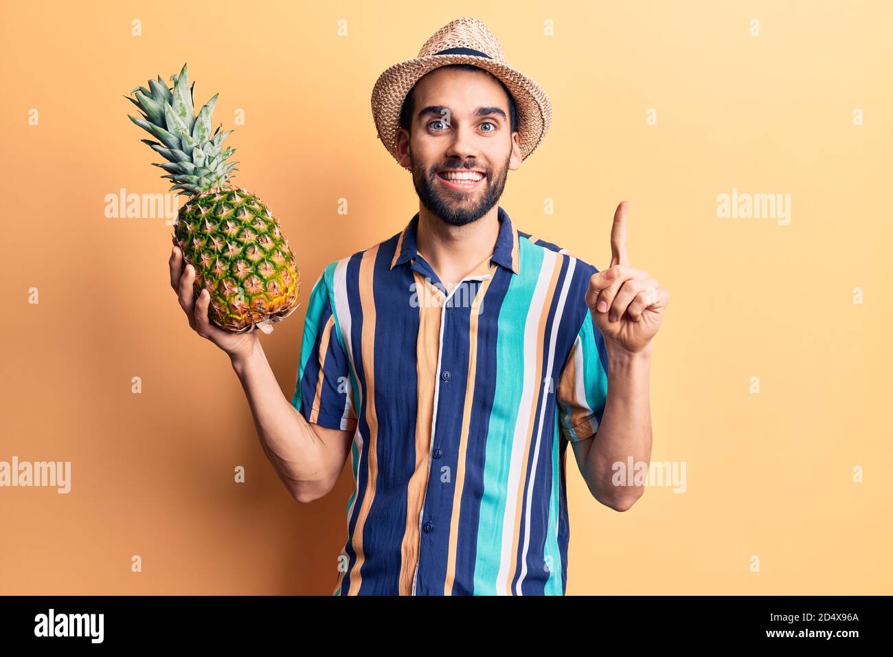 Young handsome man with beard wearing summer hat and shirt holding ...