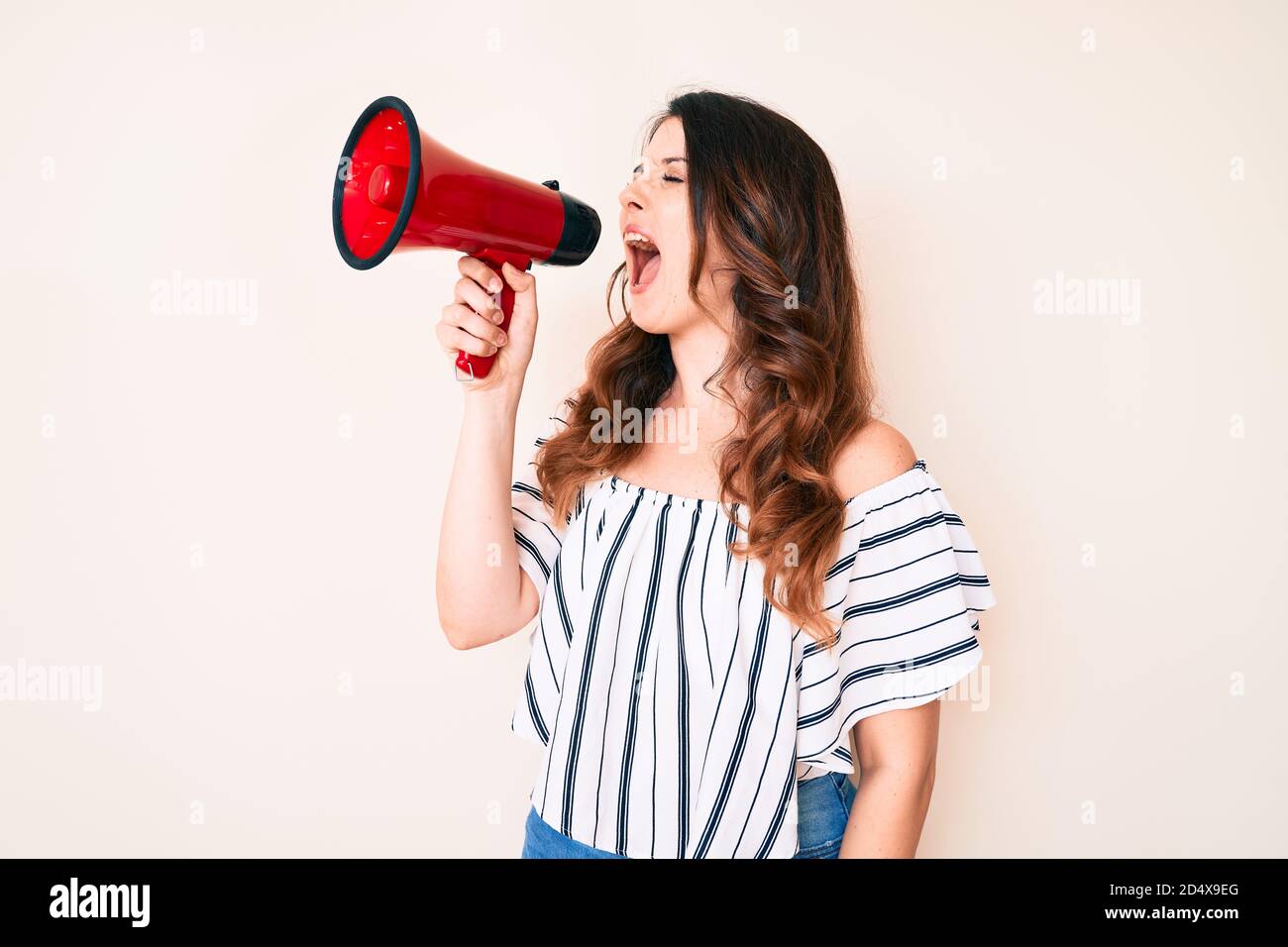 Young woman shouting exited throung megaphone, yelling and screaming ...