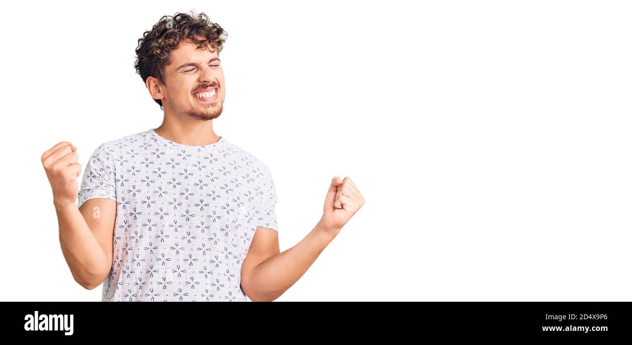 Young handsome man with curly hair wearing casual clothes very happy ...