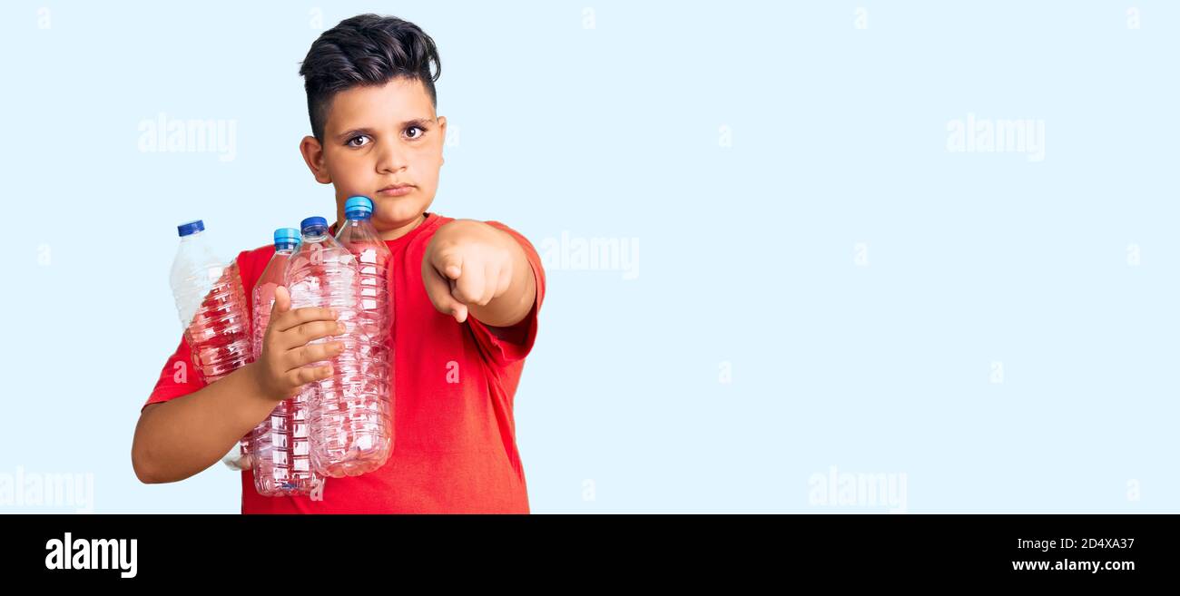 Little boy kid holding recycling plastic bottles pointing with finger ...