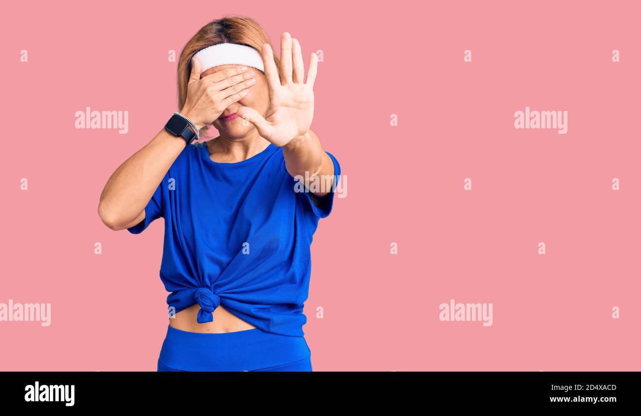 Young blonde woman wearing sportswear covering eyes with hands and ...