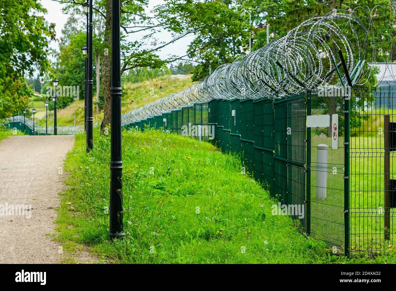 green metal fence with barbed wire around a military object Stock Photo ...