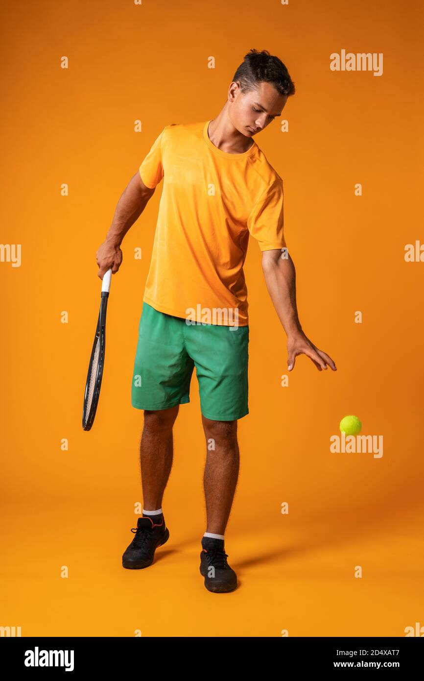 Full-length portrait of a tennis player man in action against orange ...