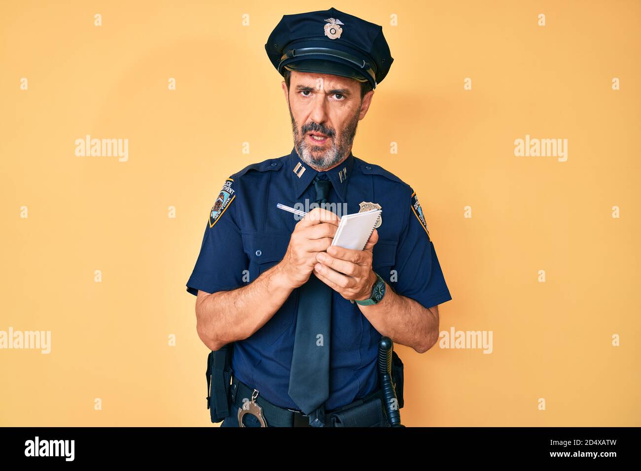 Middle age hispanic man wearing police uniform writing traffic fine in ...