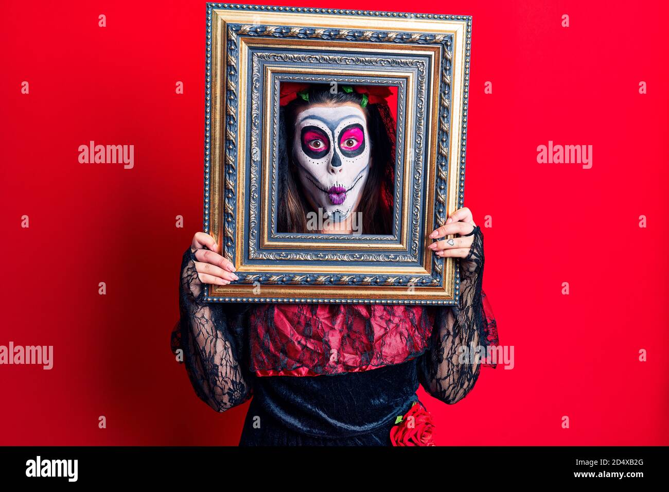 Young woman wearing day of the dead costume holding empty frame scared ...