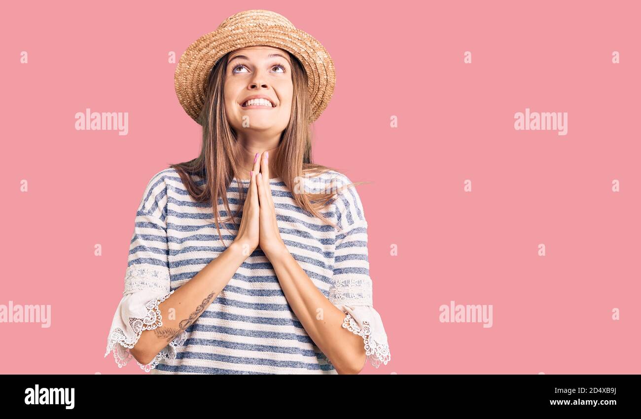 Beautiful caucasian woman wearing summer hat begging and praying with ...