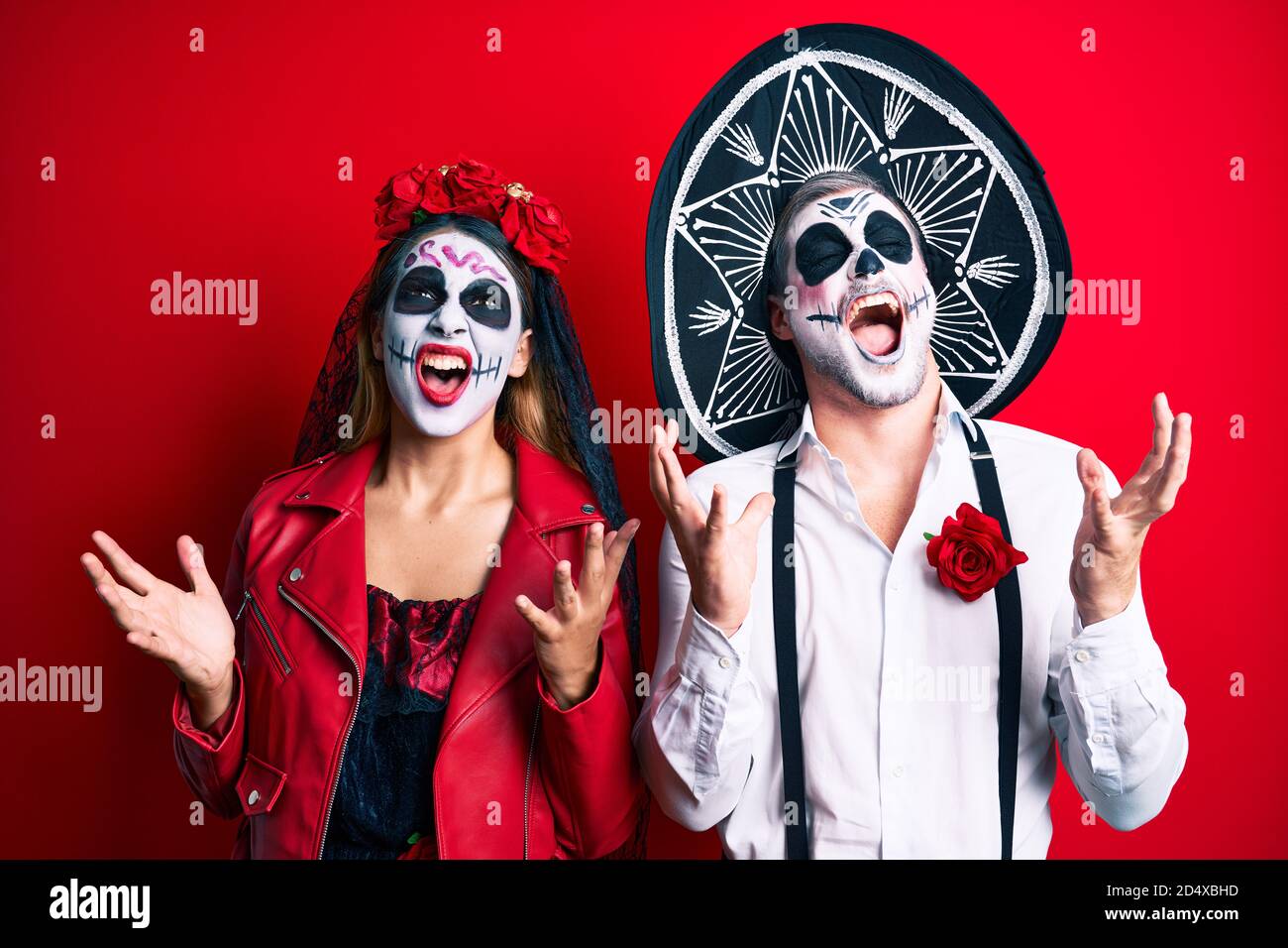 Couple wearing day of the dead costume over red crazy and mad shouting ...