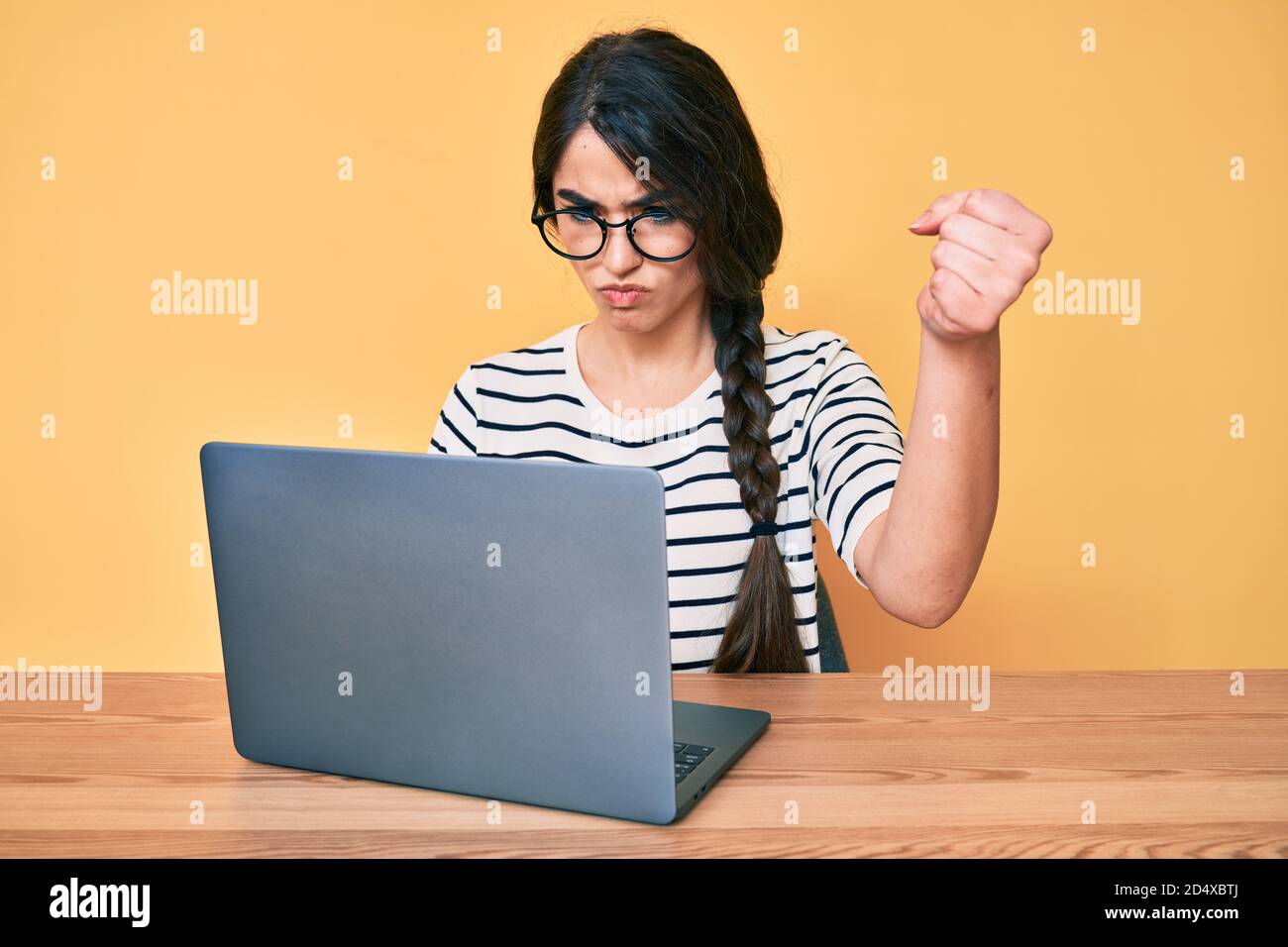 Brunette teenager girl working using computer laptop annoyed and ...