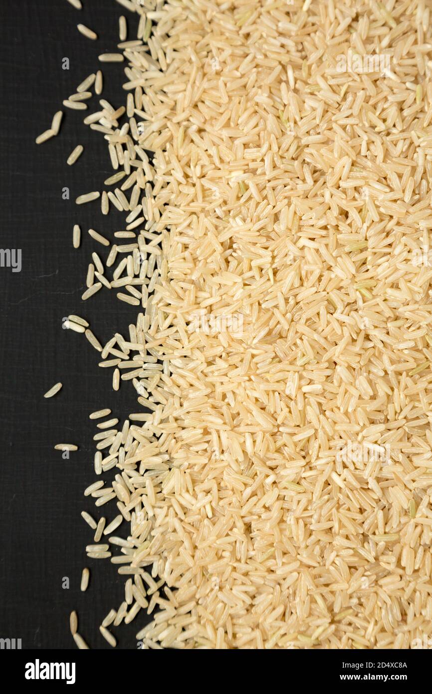 Dry Brown Rice on a black background, top view. Overhead, from above ...