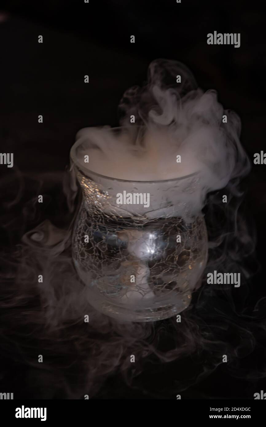 various glasses and dishes with water and dry ice smoking and bubbling ...