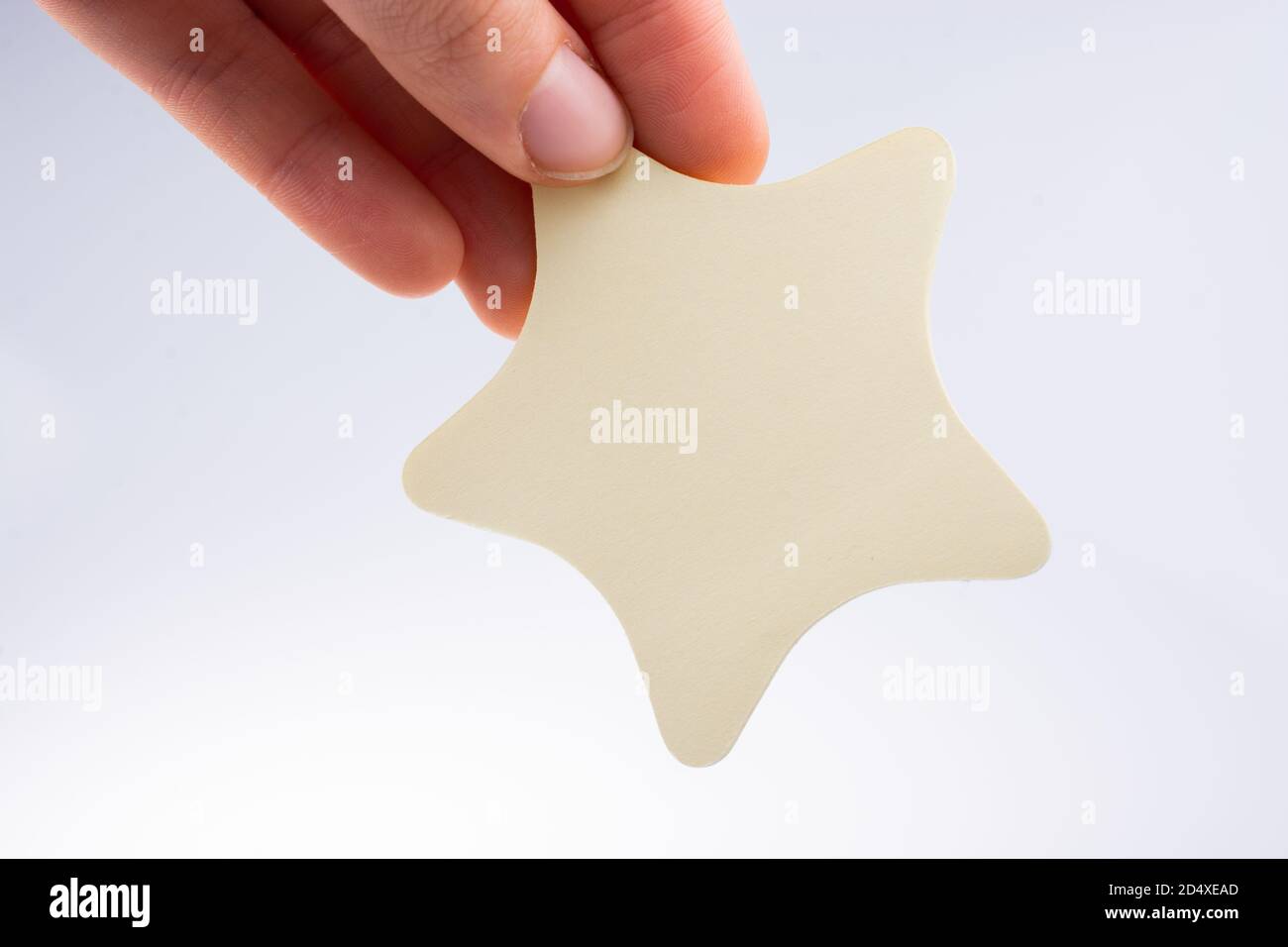 Closeup of someone holding a star-shaped paper note in front of a white ...