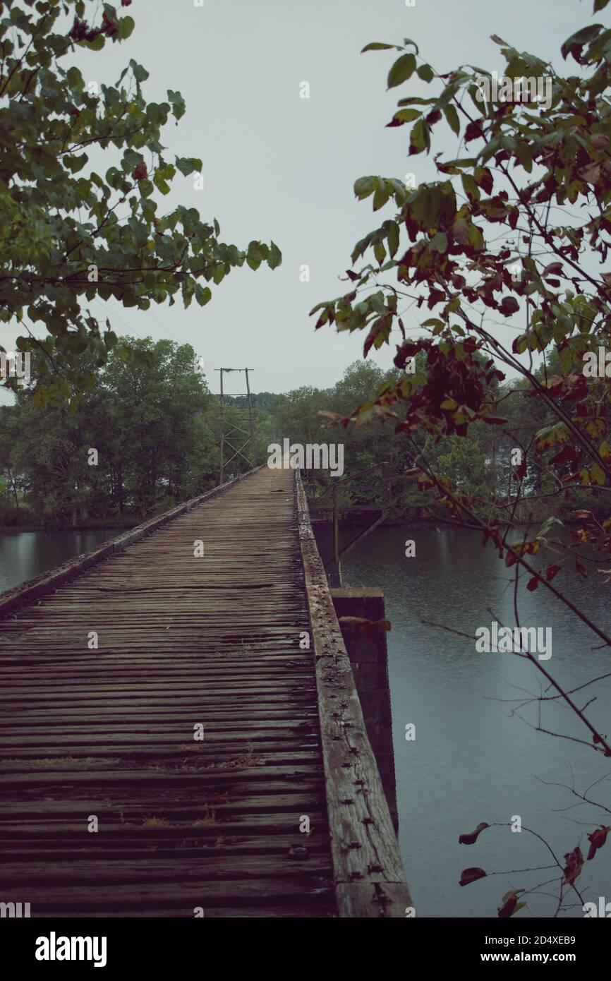 Old railroad wood bridge across water with trees are both sides of the ...