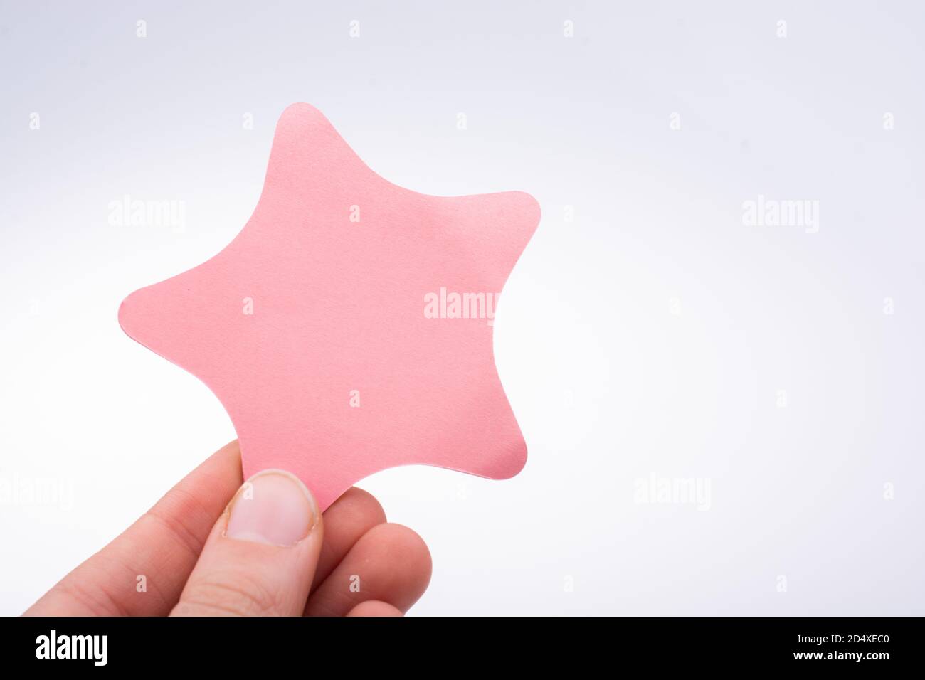 Closeup of someone holding a star-shaped paper note in front of a white ...