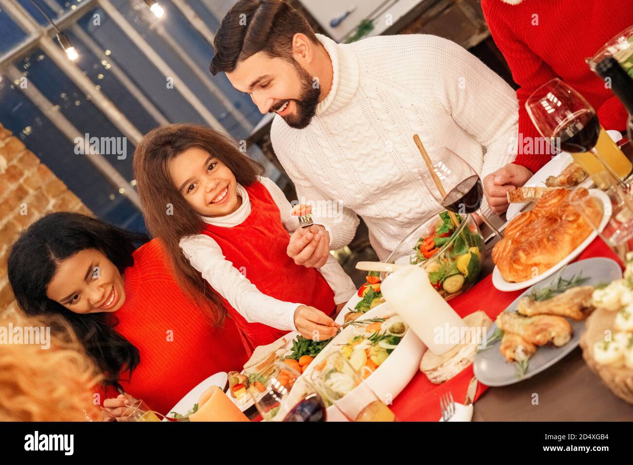 Mixed race family sitting behind served dinner table Stock Photo - Alamy