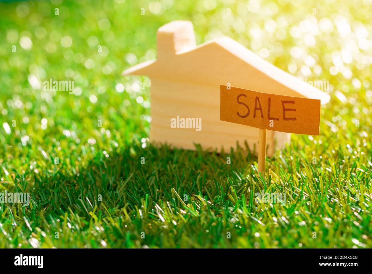 Wooden toy house on grass with sale sign Stock Photo - Alamy