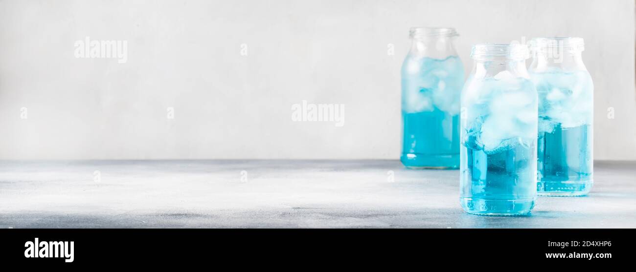 Summer refreshing cold drink, isotonic blue water in bottles, gray ...