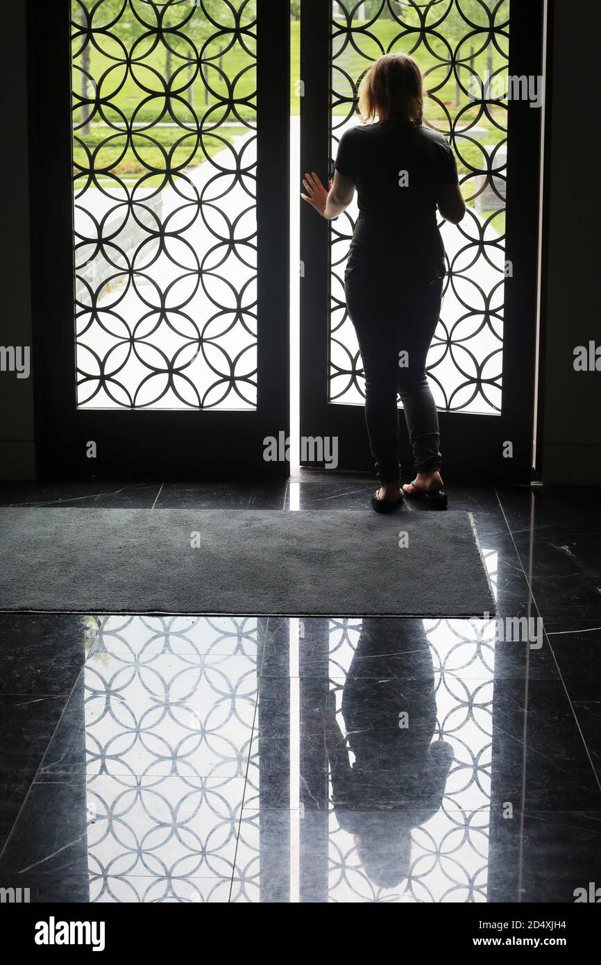 A young woman looking out an ornate large metal door Stock Photo - Alamy