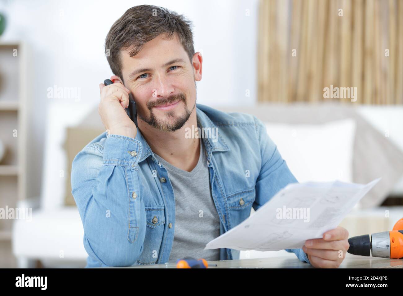 male diy expert using smartphone and holding instructions Stock Photo ...