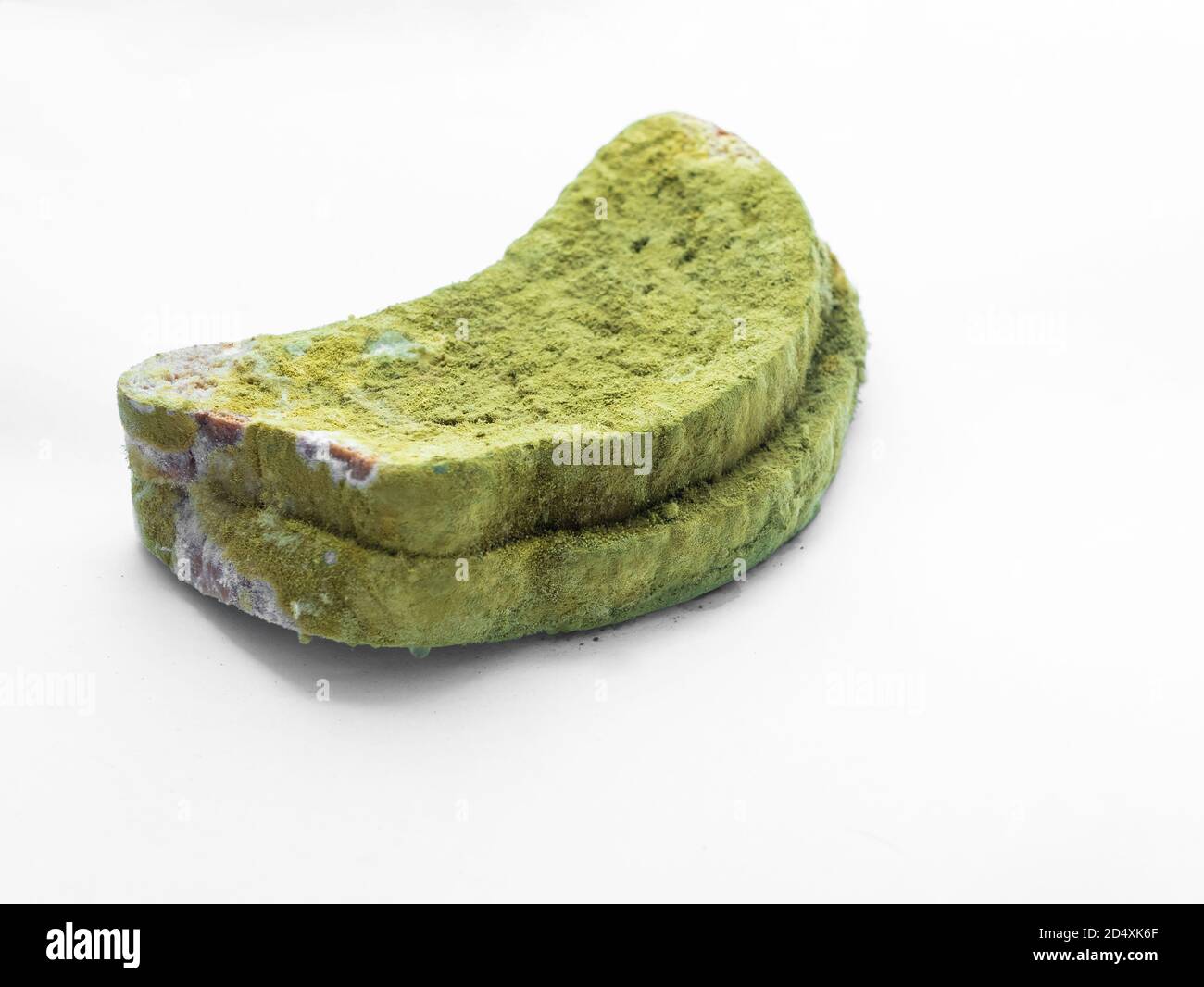 A piece of bread covered with green mold on a white background isolate ...