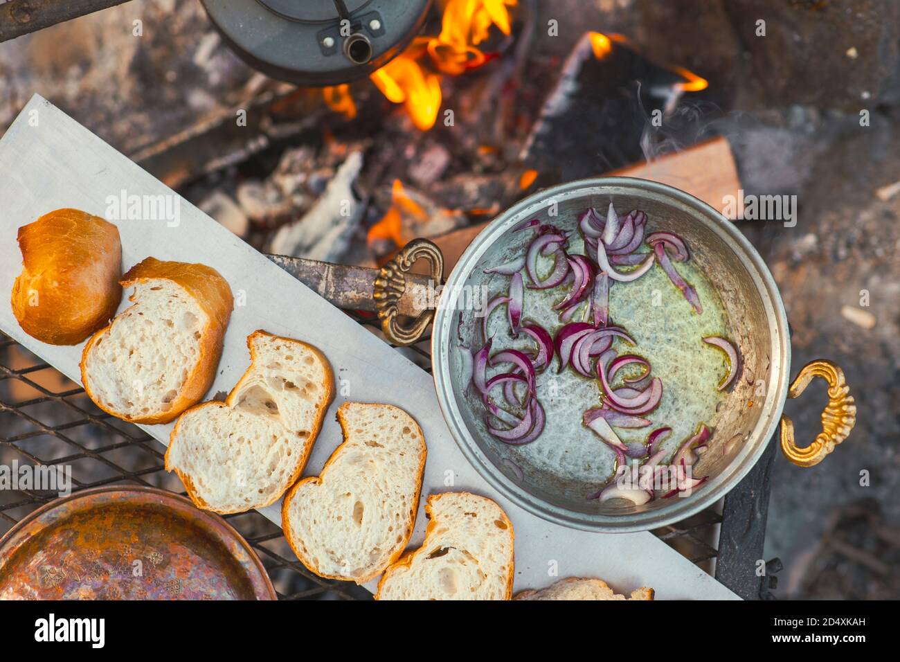 Flat lay view of camp fire cooking, breads are in a row, a tea pot and ...