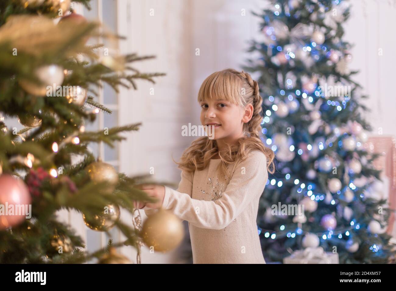 Little girl spends time decorating the Christmas tree. Preparing for ...