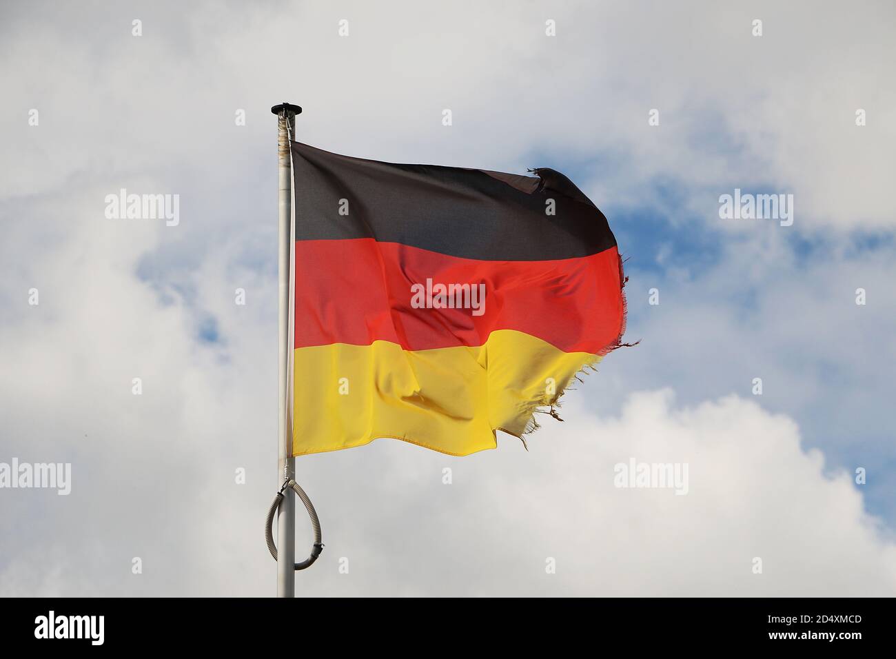 Low angle shot of the waving German flag on a pole under a cloudy sky ...