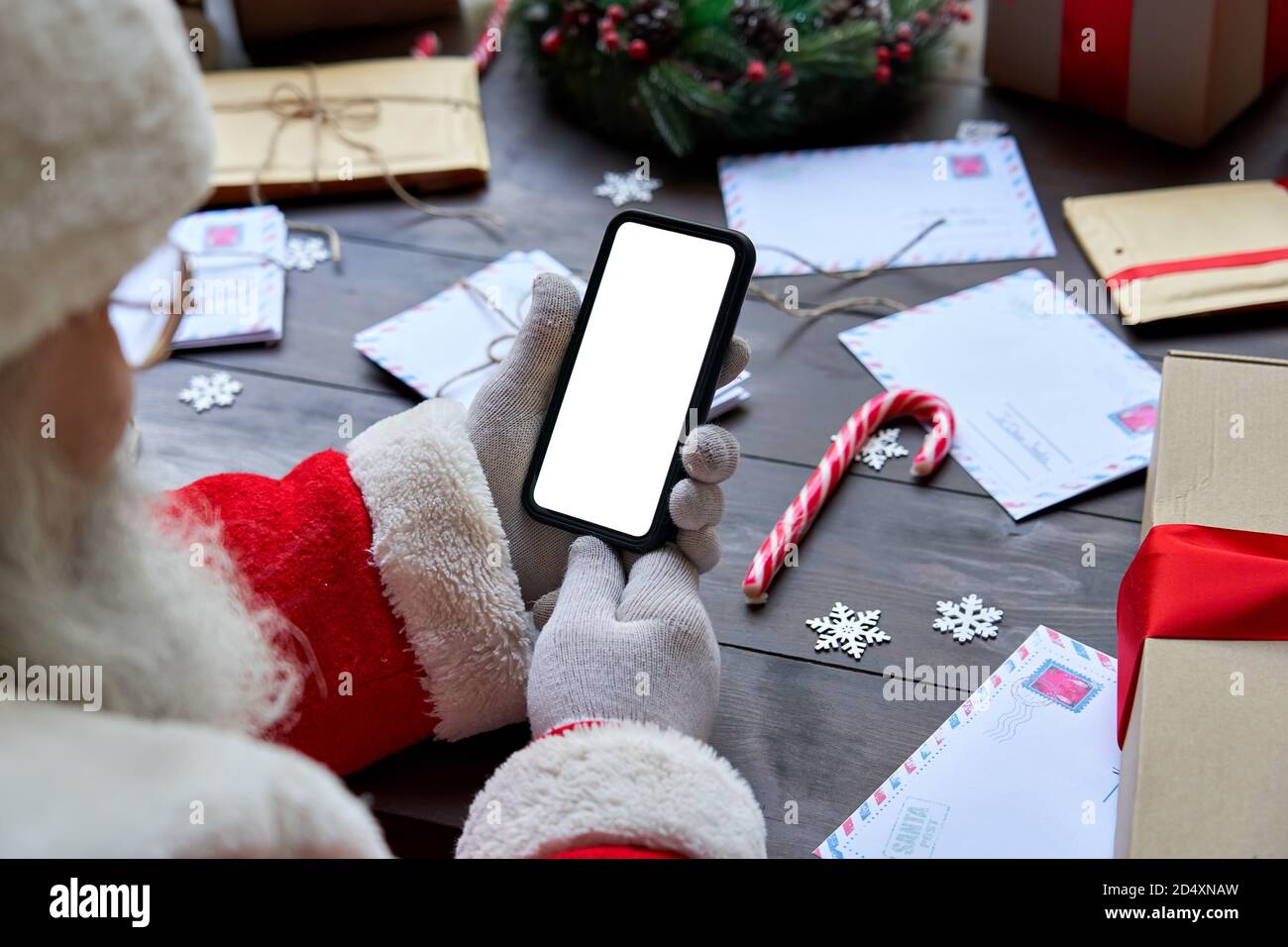 Over shoulder of Santa holding smartphone with white screen using ...
