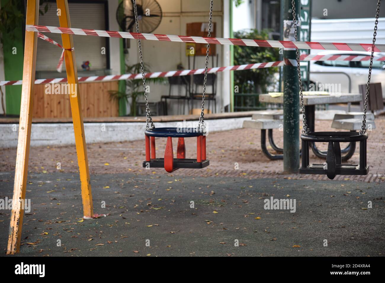 An empty children's swing..Barricade Tape, red and white striped ...