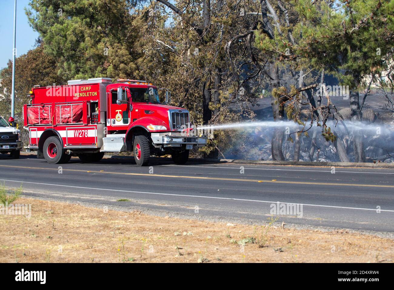 A fire truck with Camp Pendleton Fire Department sprays water on a fire on Marine Corps Base ...