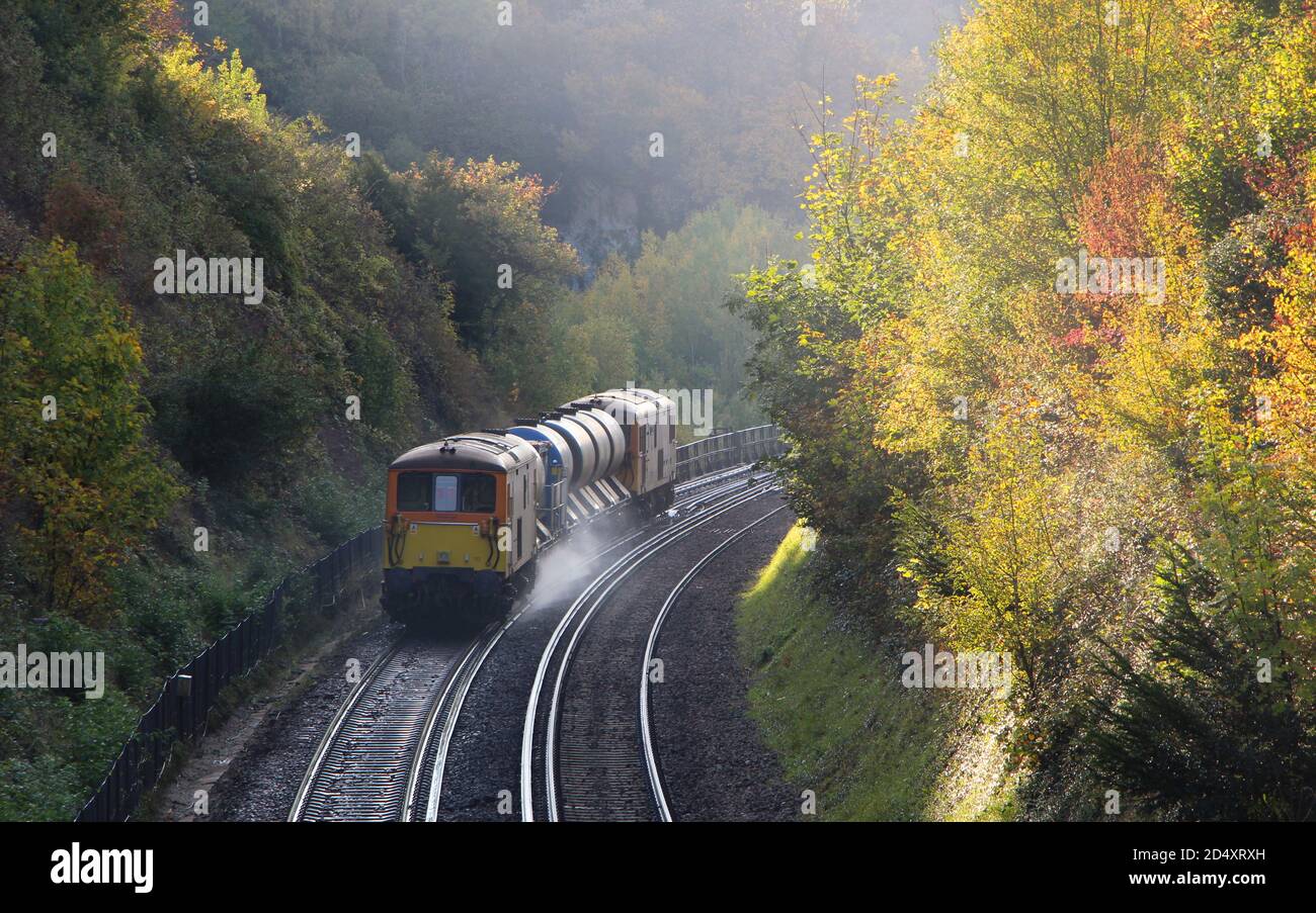 Train cleaning leaf residue from tracks in early autumn in a cutting ...