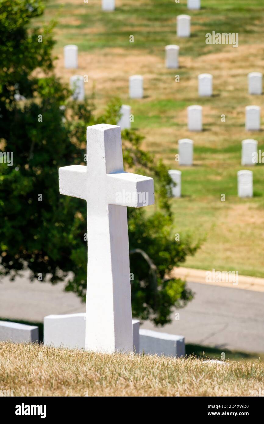 Cross and tombstones on a grassy hill at Arlington National Cemetery ...
