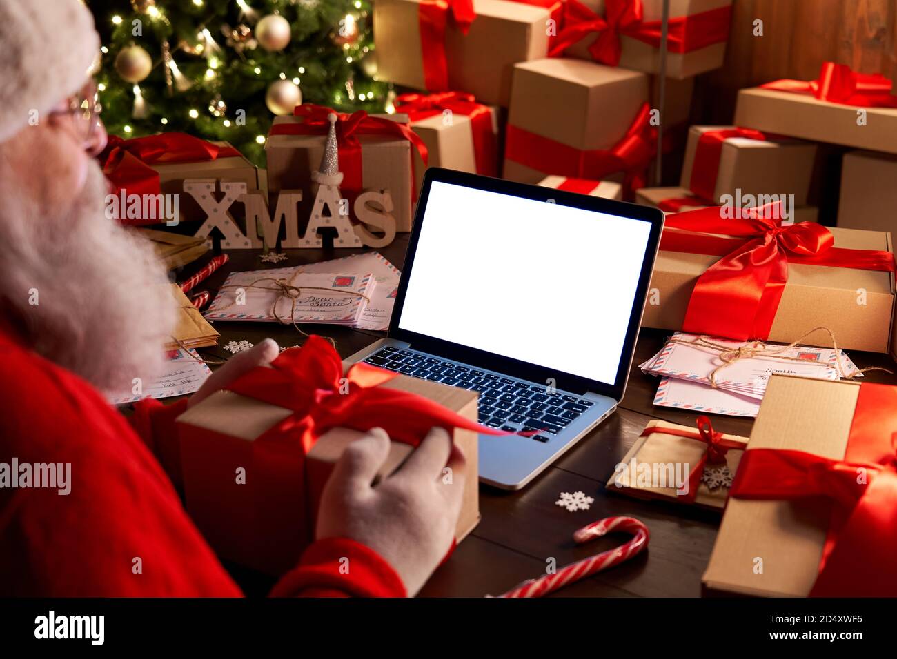 Santa Claus holding gift using laptop computer mock up white screen ...