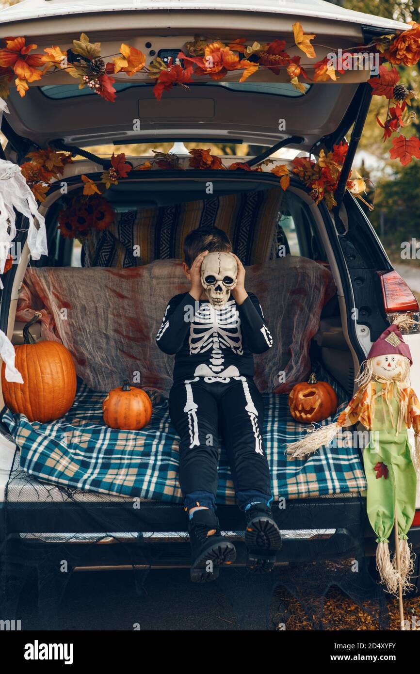 Trick or trunk. Boy child with human skull celebrating Halloween in ...