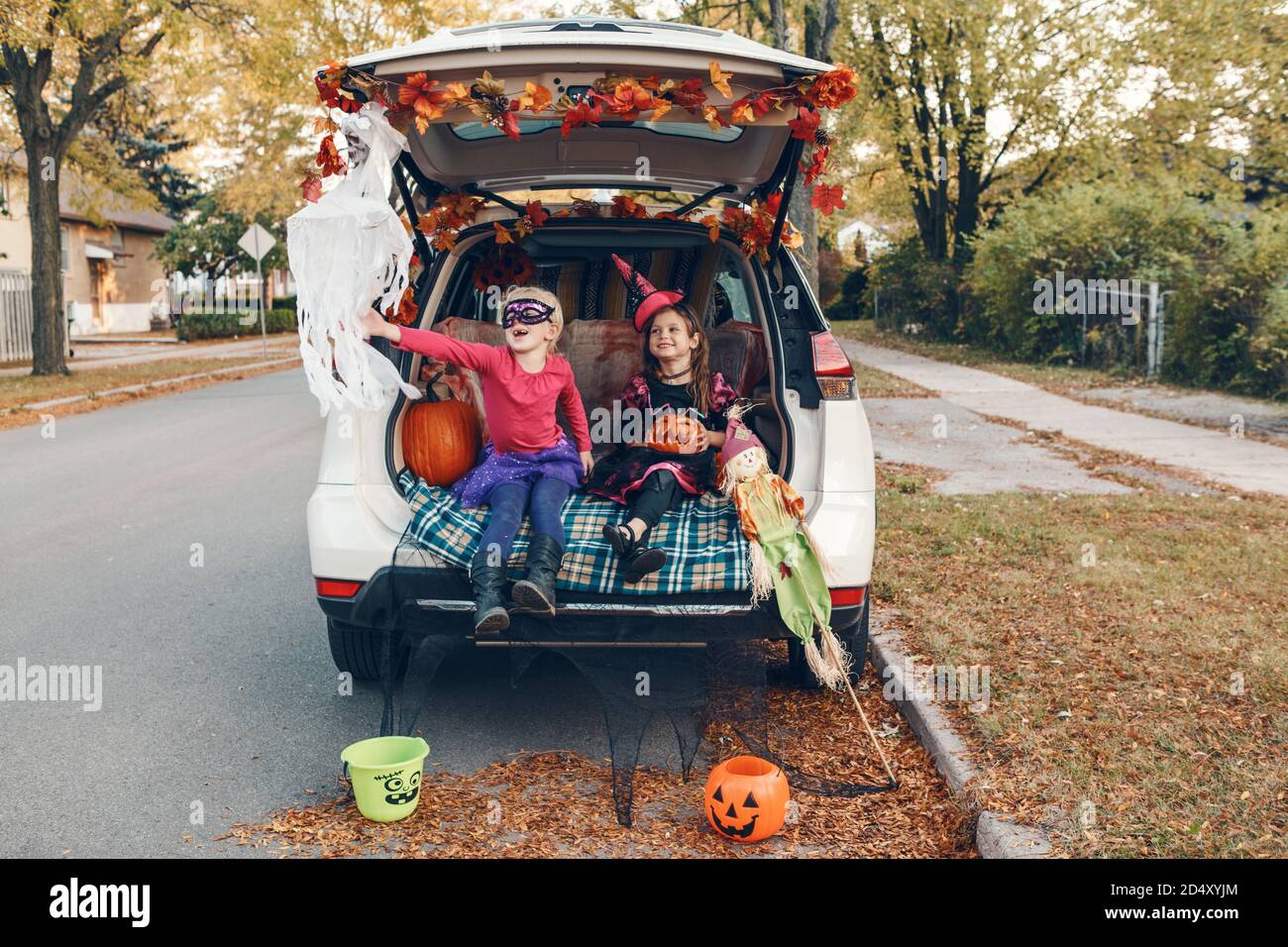 Trick or trunk. Children siblings sisters celebrating Halloween in ...