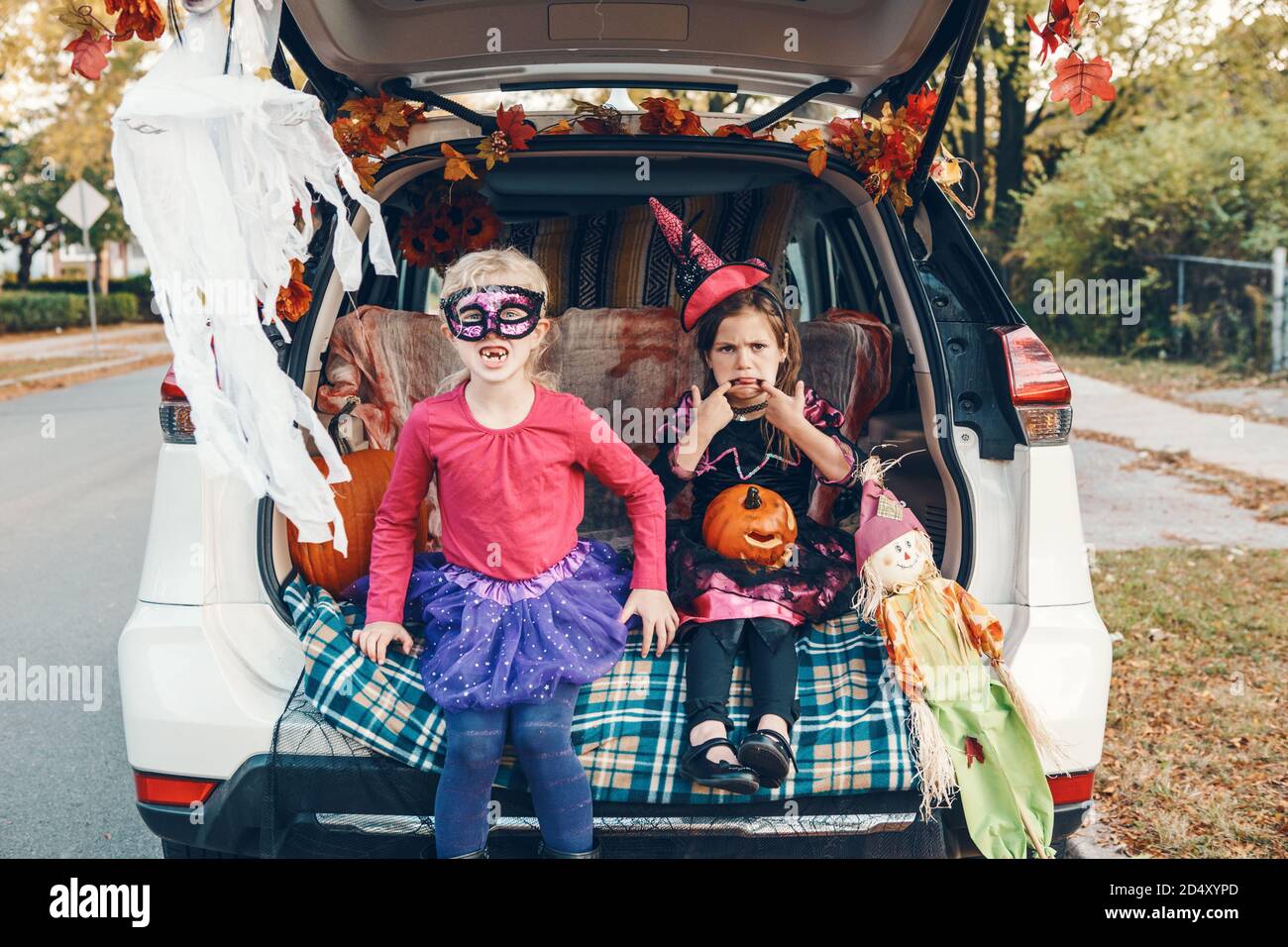 Trick or trunk. Children siblings sisters celebrating Halloween in ...