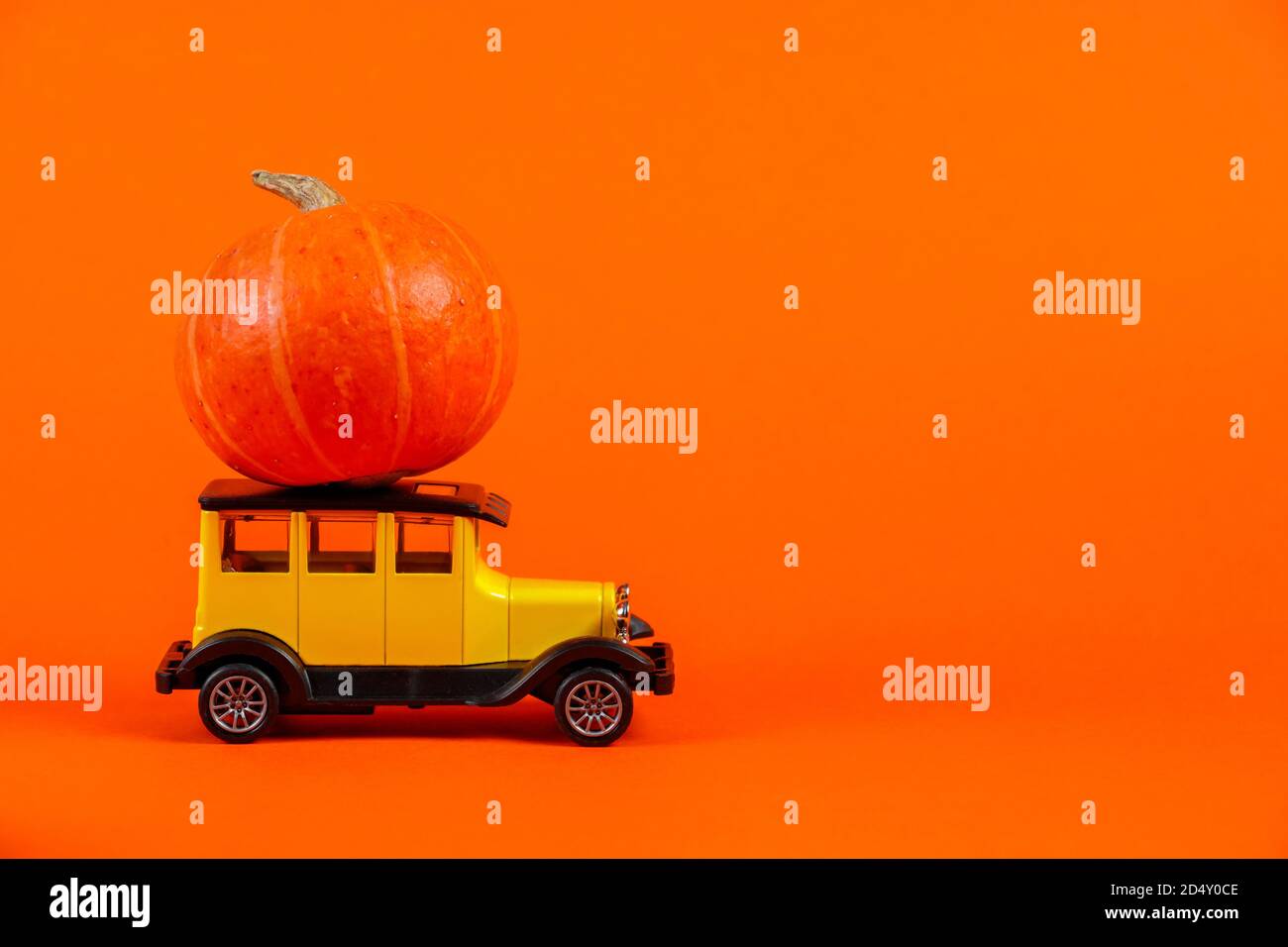Retro toy car with a pumpkin on an orange background. Halloween and ...