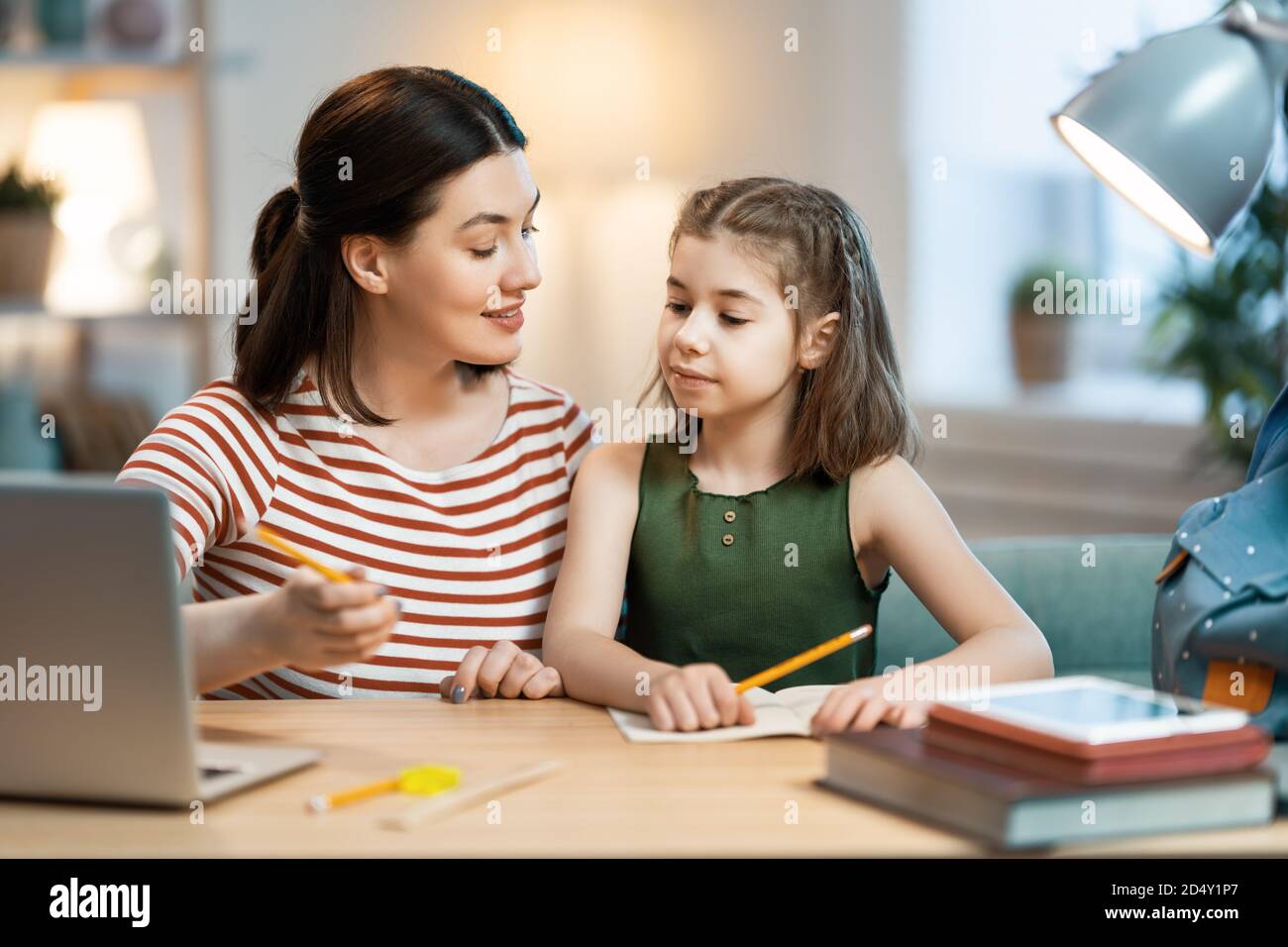 Back to school. Happy child and adult are sitting at desk. Girl doing ...