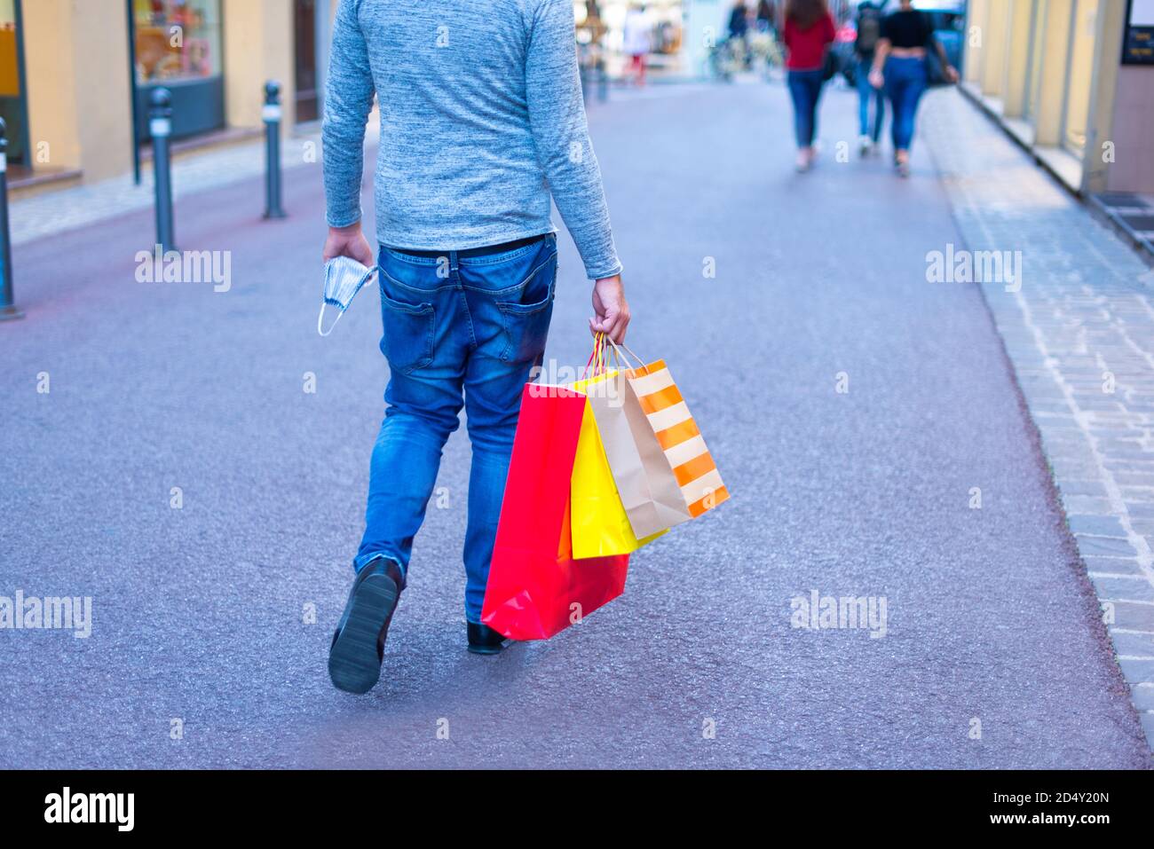 man alone walking in the city center holding shopping paper bags and a ...