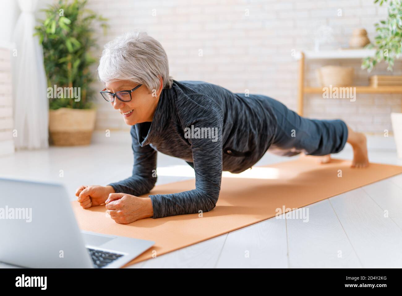 Senior woman in activewear watching online courses on laptop while ...