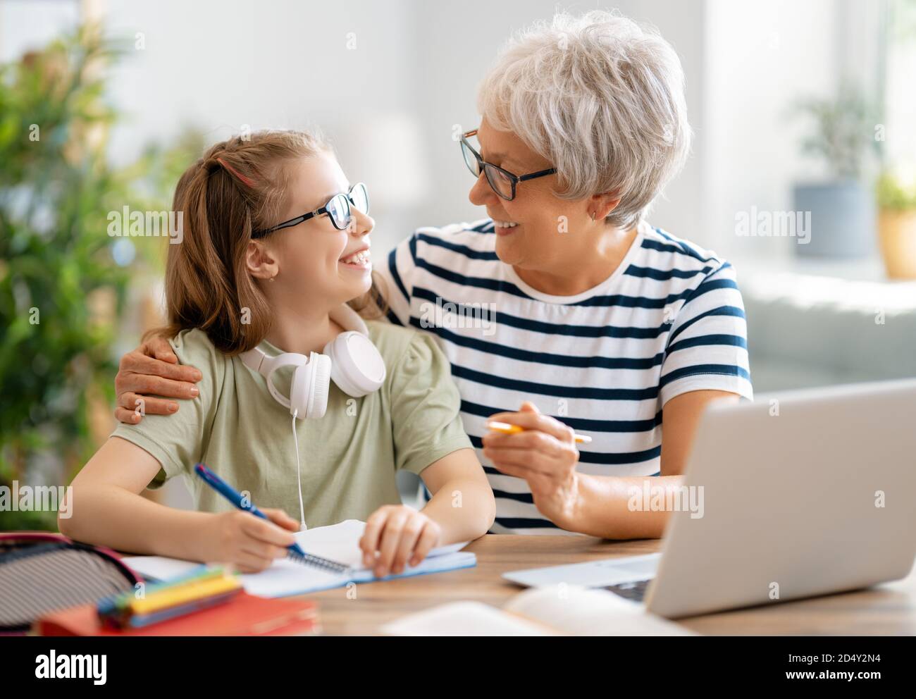 Back to school. Happy child and adult are sitting at desk. Girl doing ...