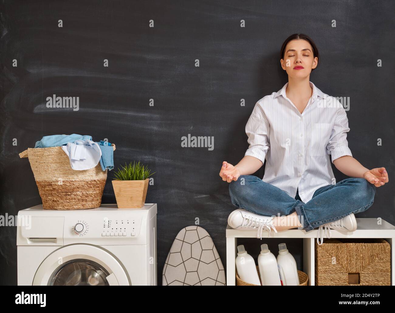 Beautiful young woman is smiling while doing laundry at home Stock ...