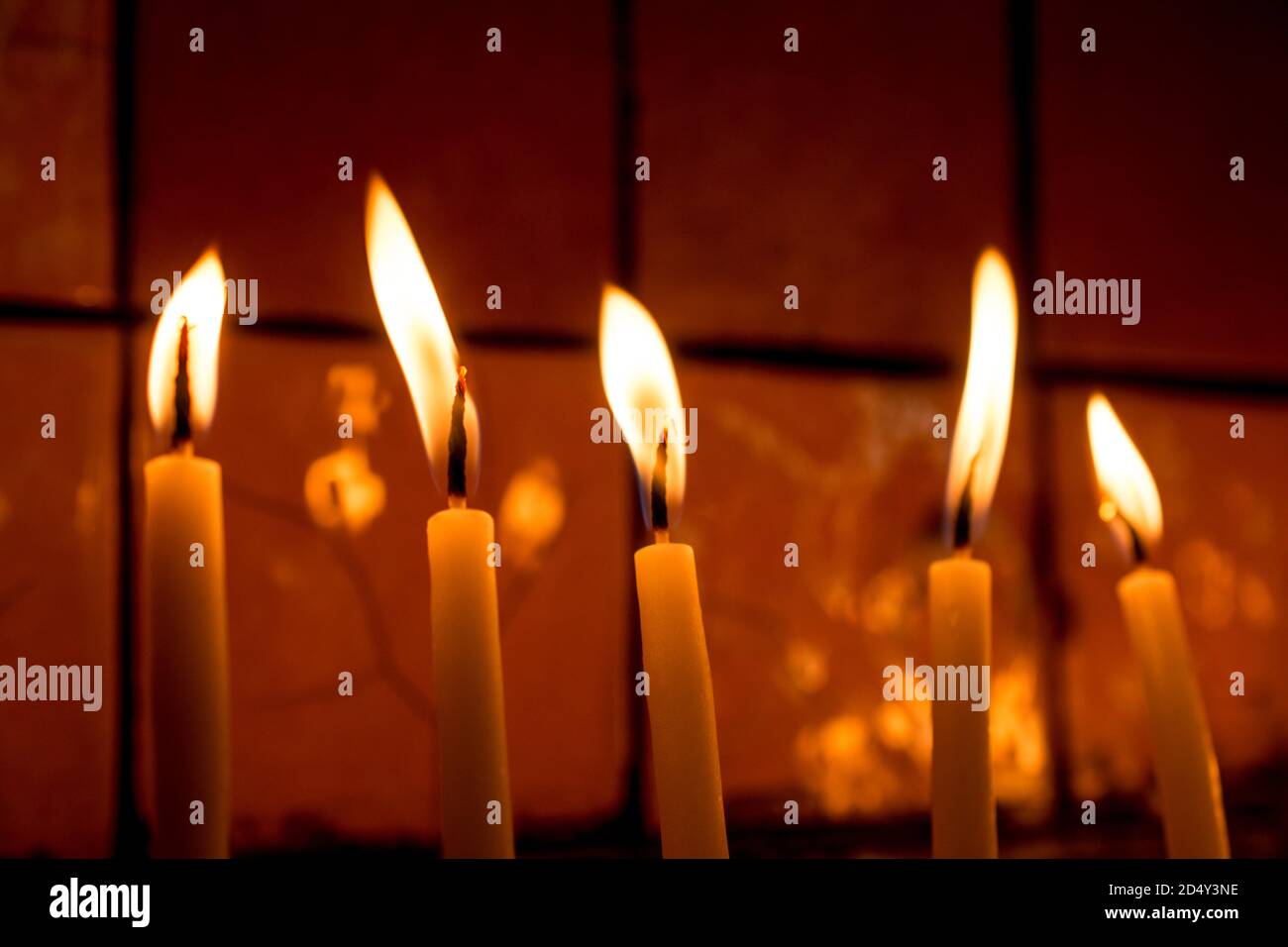 Candles burning with yellow flames in the dark Stock Photo - Alamy