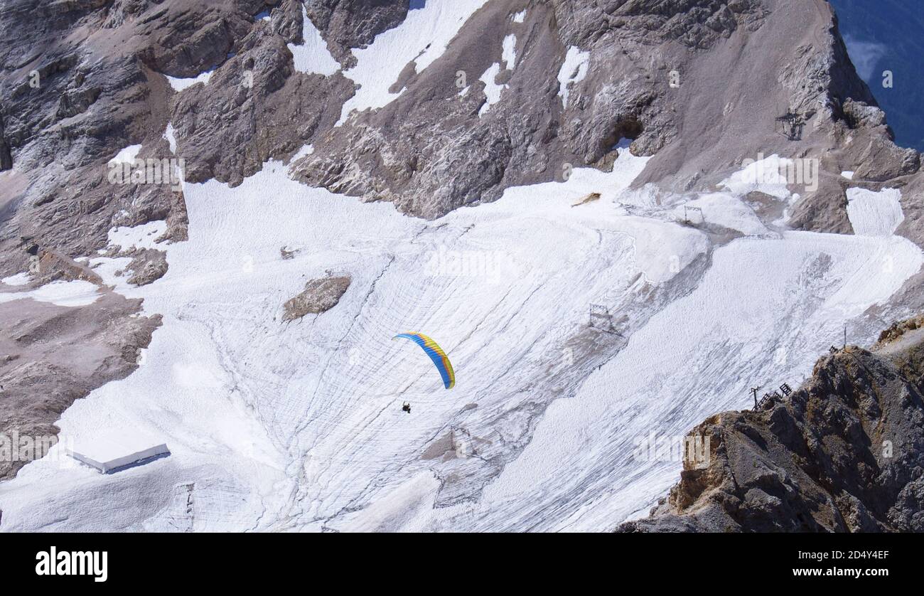 Person paragliding from the top of Zugspitze Mountain with jagged ...
