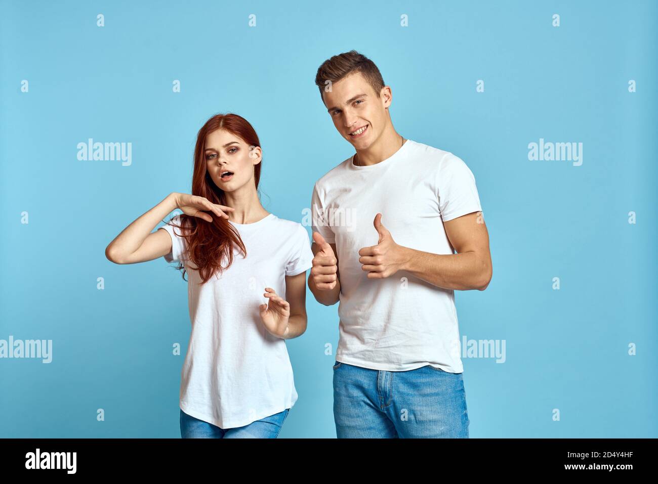 enamored man and woman in jeans and a T-shirt on a blue background hug ...