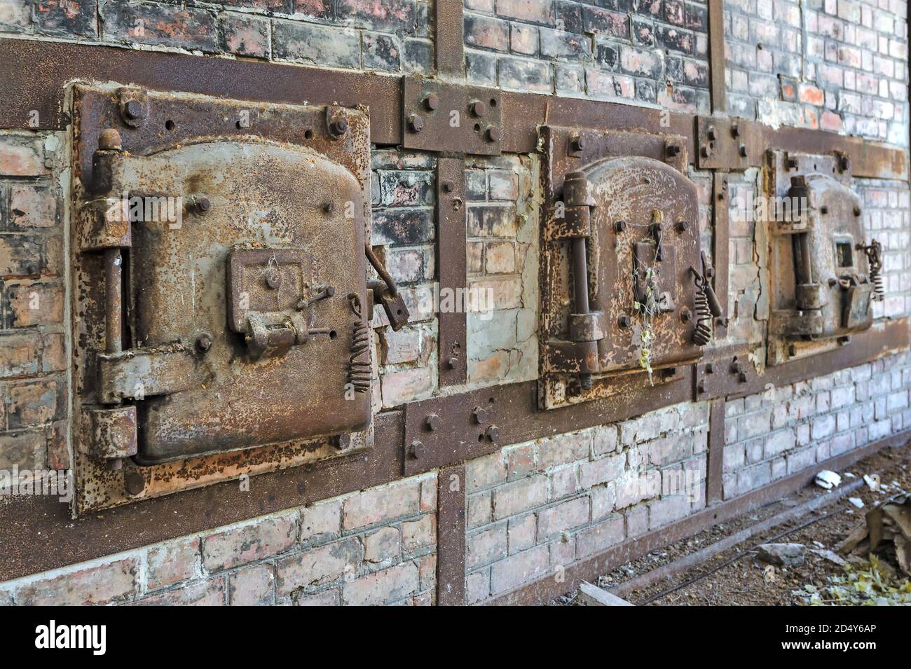A row of rusty old metal hatch doors of a red brick kiln in an ...