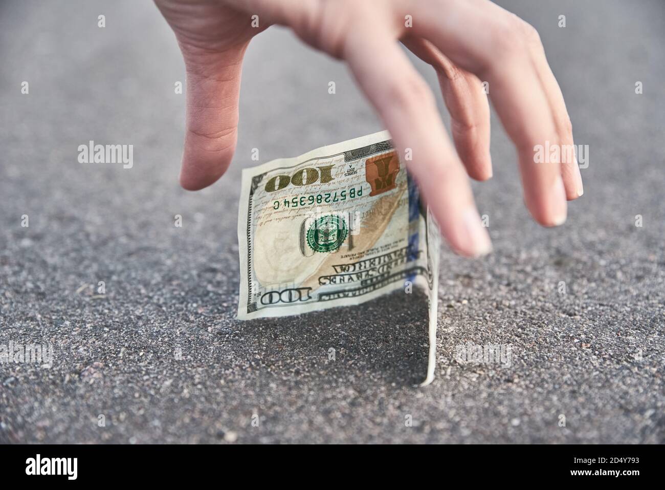 Hand picking one hundred dollar banknote from ground. Found money ...