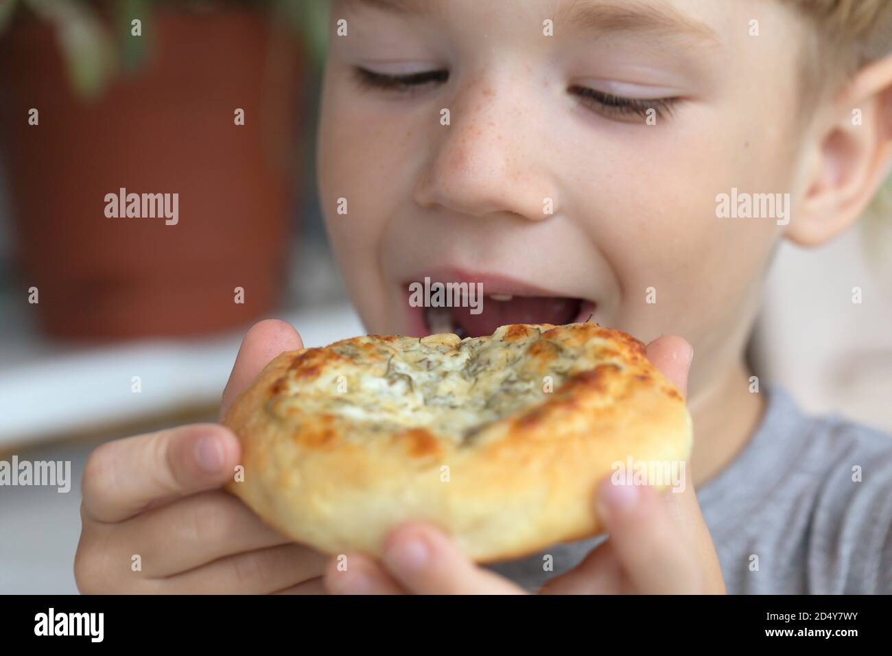 Happy little boy eating cheese bun in cafe outdoors Stock Photo - Alamy