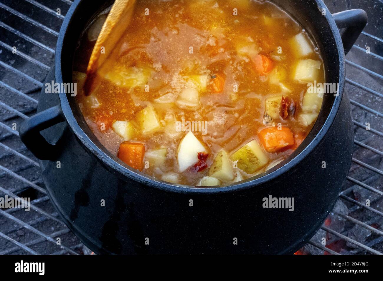 Stew cooked on fire outdoors in a cast-iron pot on a grill grid Stock ...