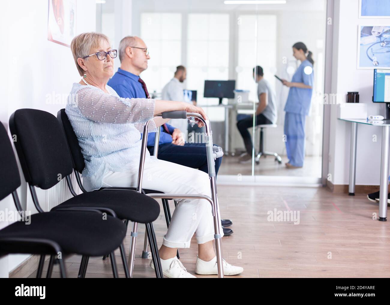 Senior woman with walking frame in hospital waiting room for ...