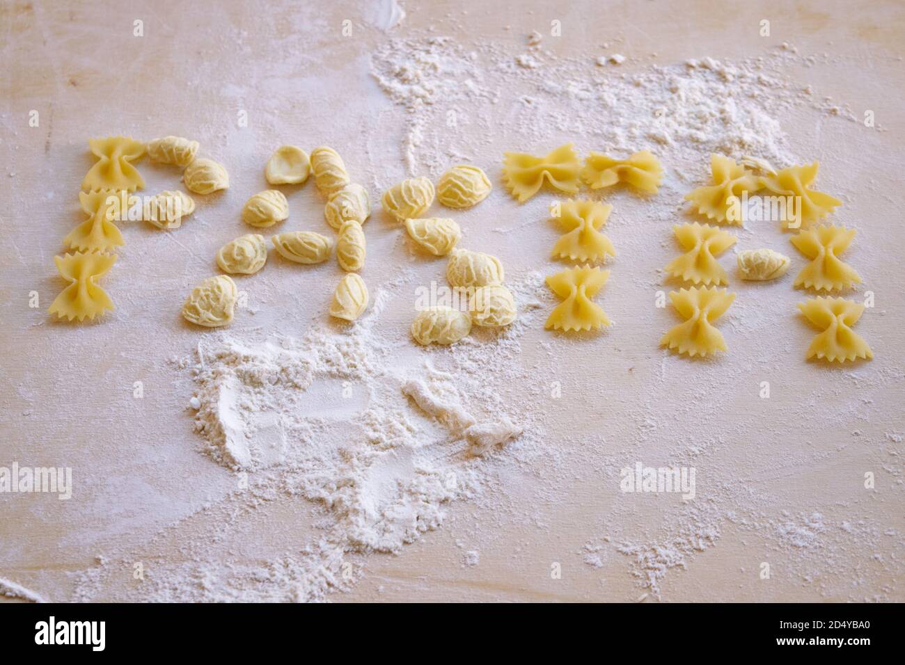 writing pasta between the flour on a wooden board Stock Photo - Alamy